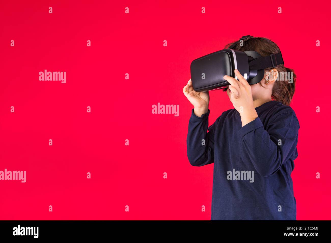 Side view of little girl wearing virtual reality goggles amazed and ...