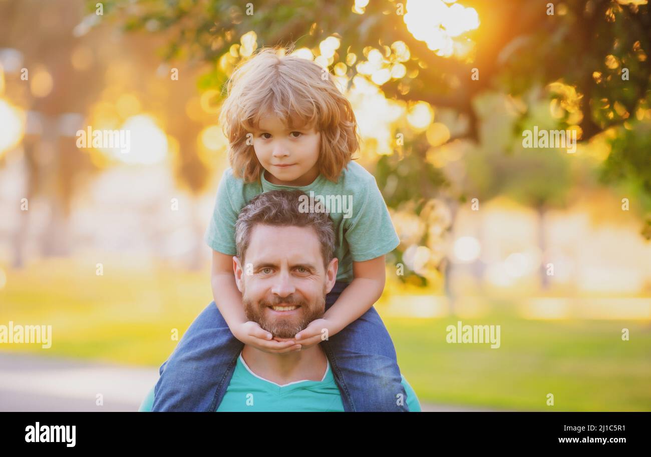 Father giving son ride on back in park. Portrait of happy father giving ...