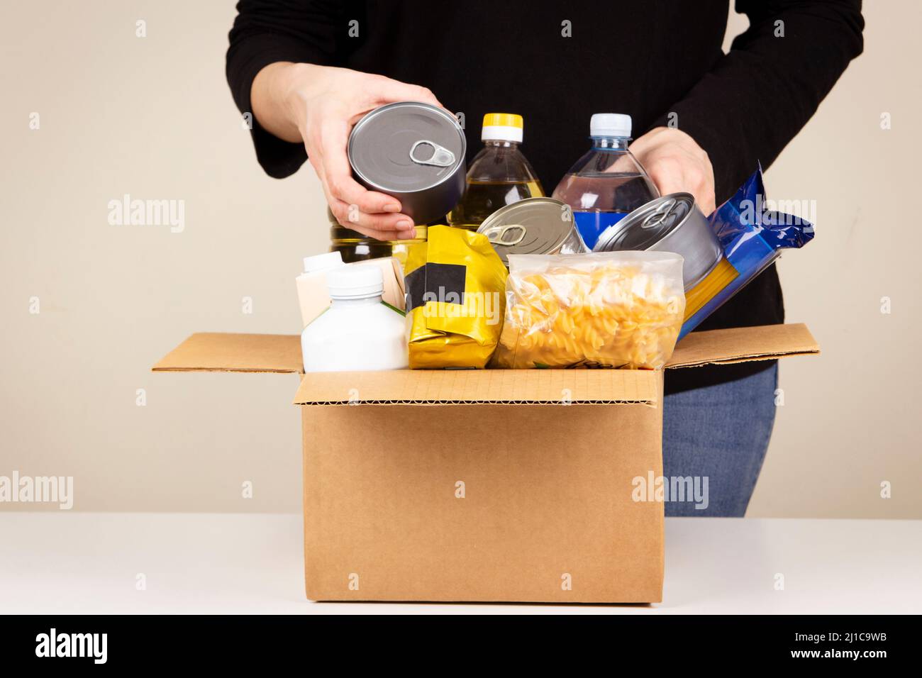 Volunteer woman hands collecting food into donation box. Cardbox full ...