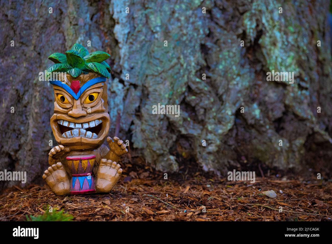 A tiki toga statue of a smiling little man with big feet and a small ...