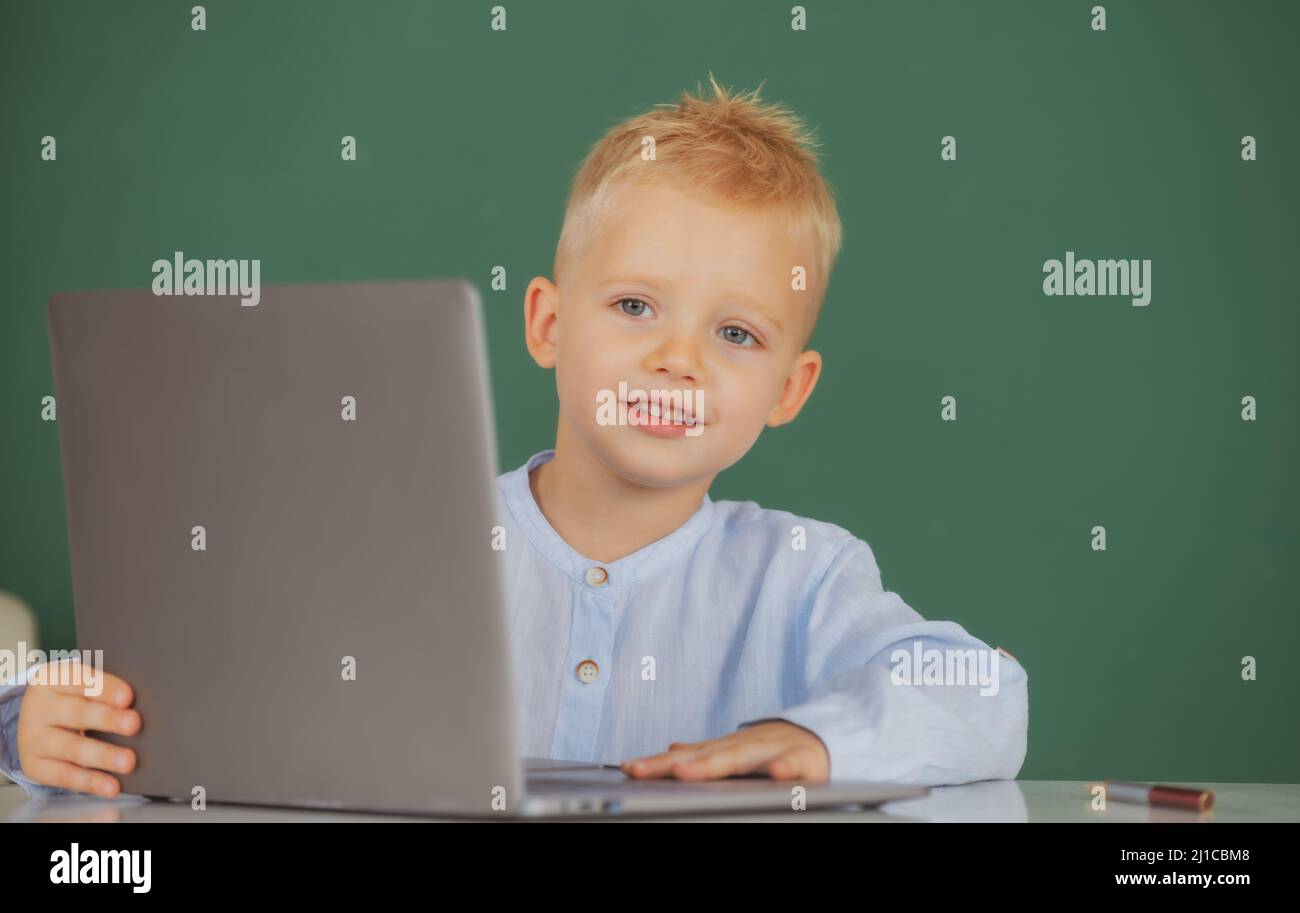 Child boy using a laptop computer at school. Cute pupil face closeup on ...