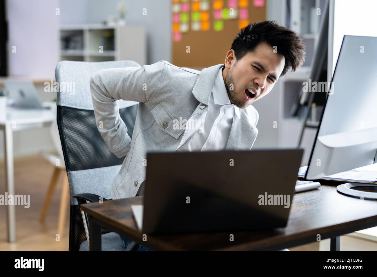 Back Pain Bad Posture Man Sitting In Office Stock Photo - Alamy