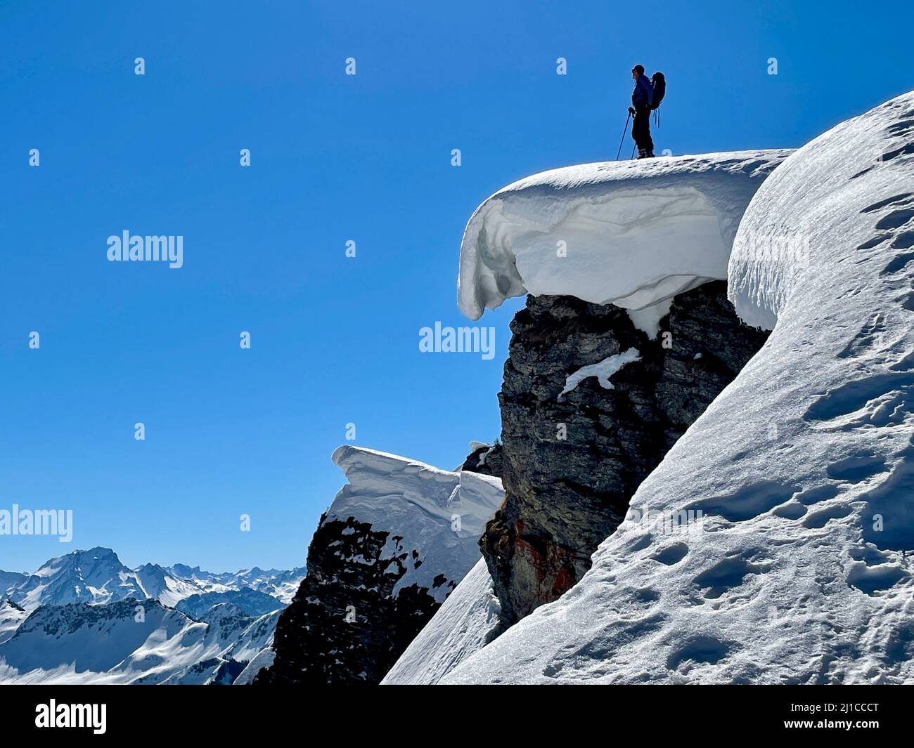 Freerider standing on snowcapped cliff close to edge enjoying ...