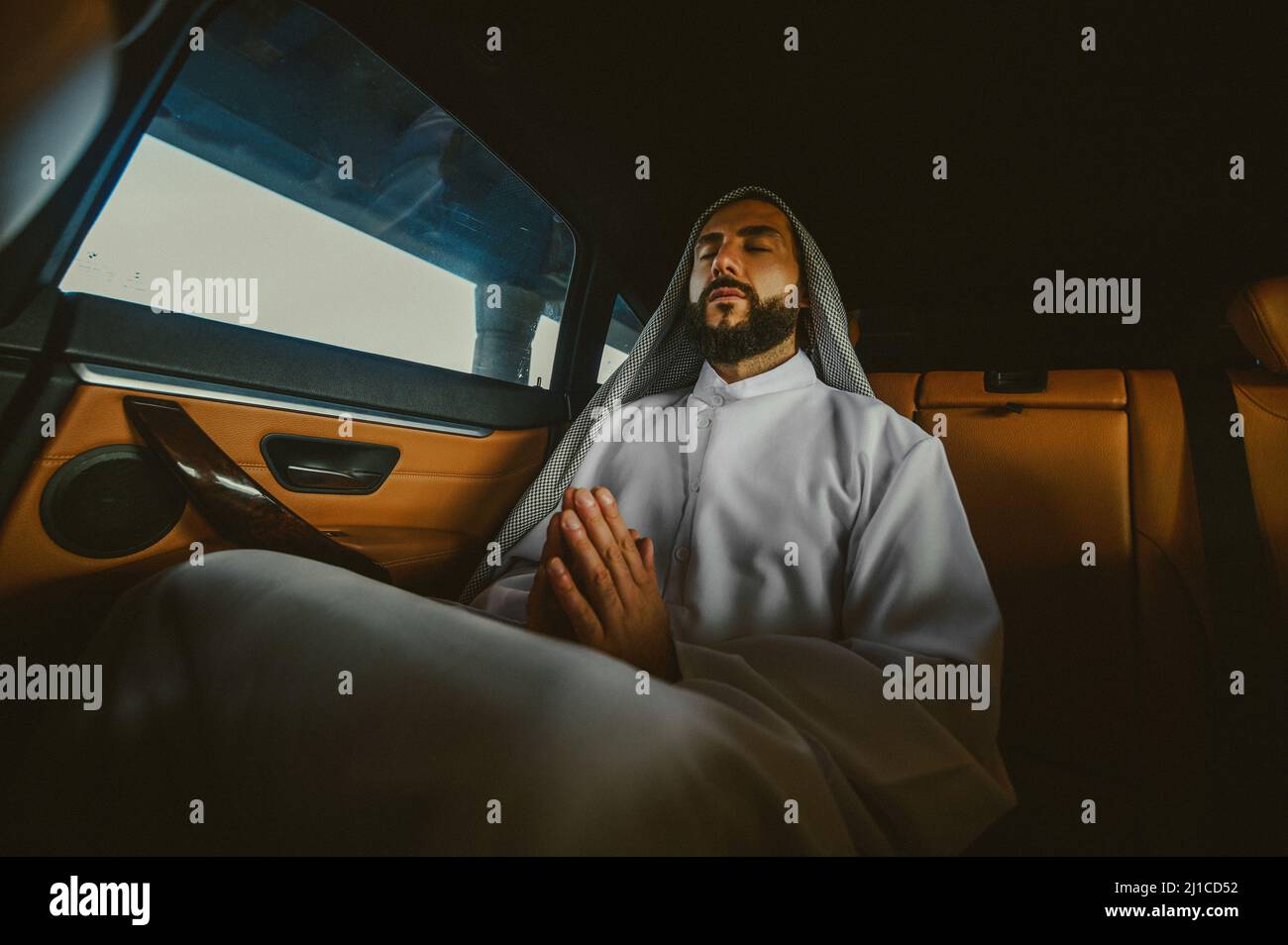 A young rich saudi in a leather car interior parying Stock Photo - Alamy
