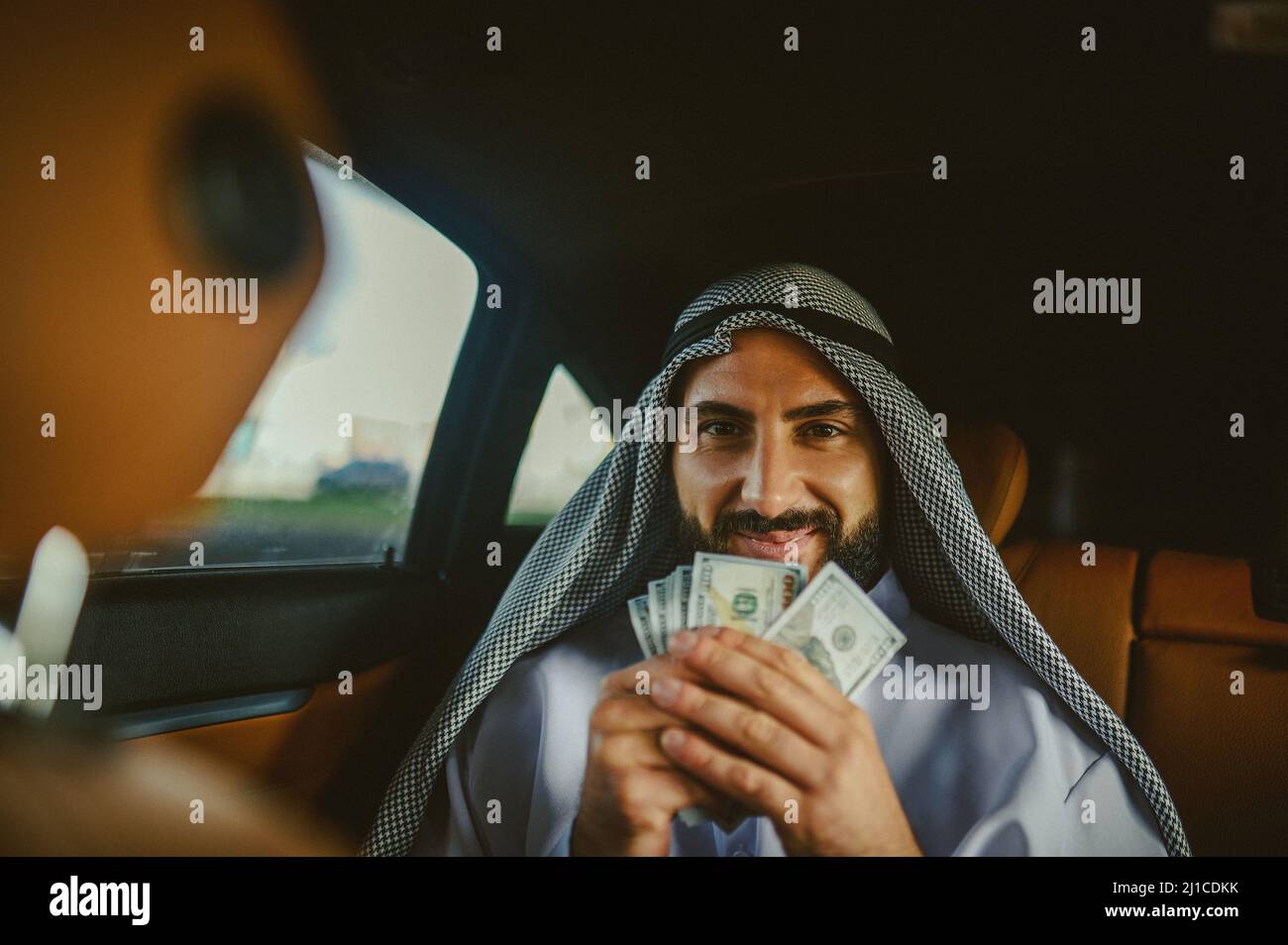 Saudi man in a traditional clothing in a car holding money Stock Photo ...