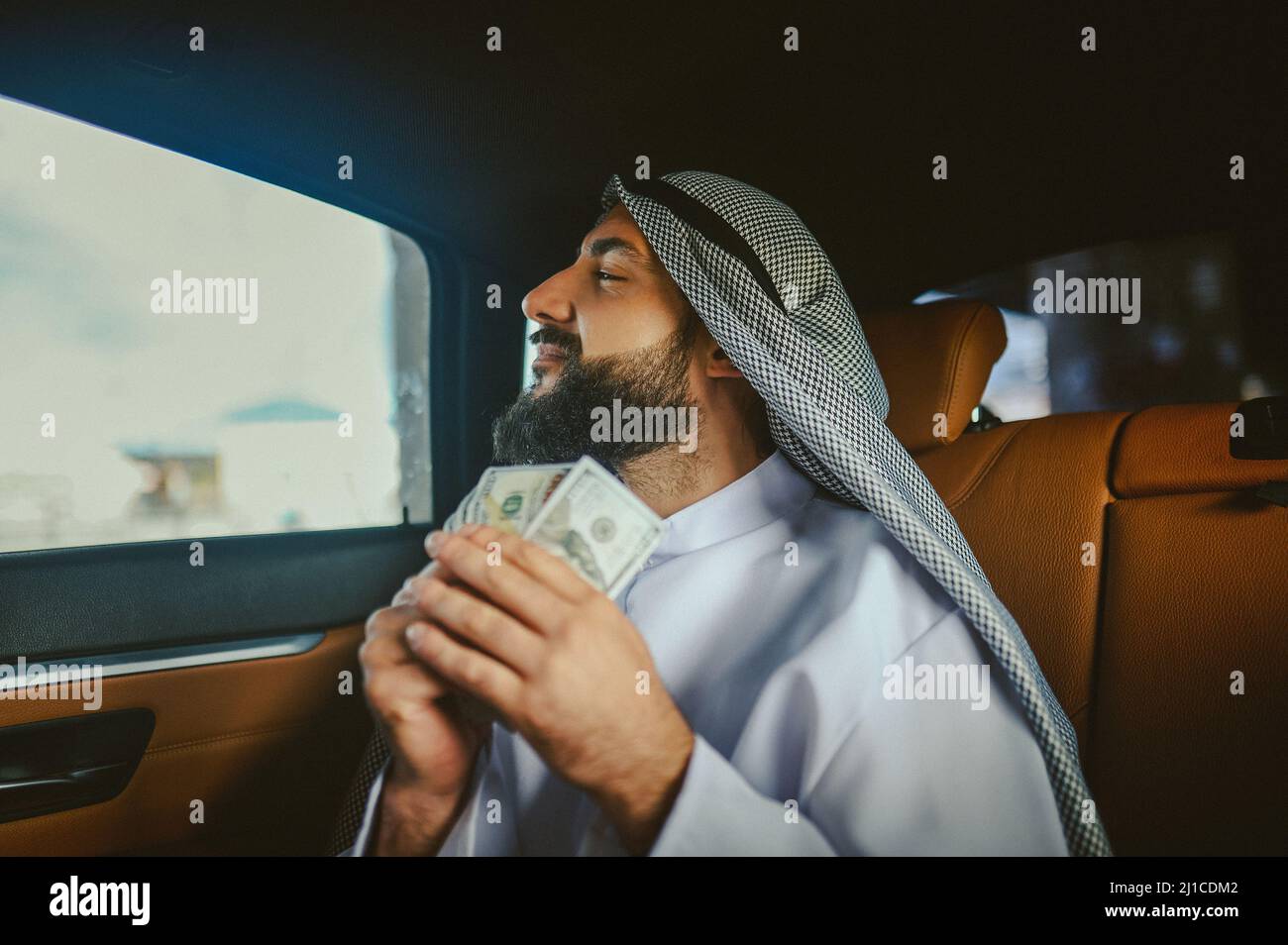 Saudi man in a traditional clothing in a car holding money Stock Photo ...