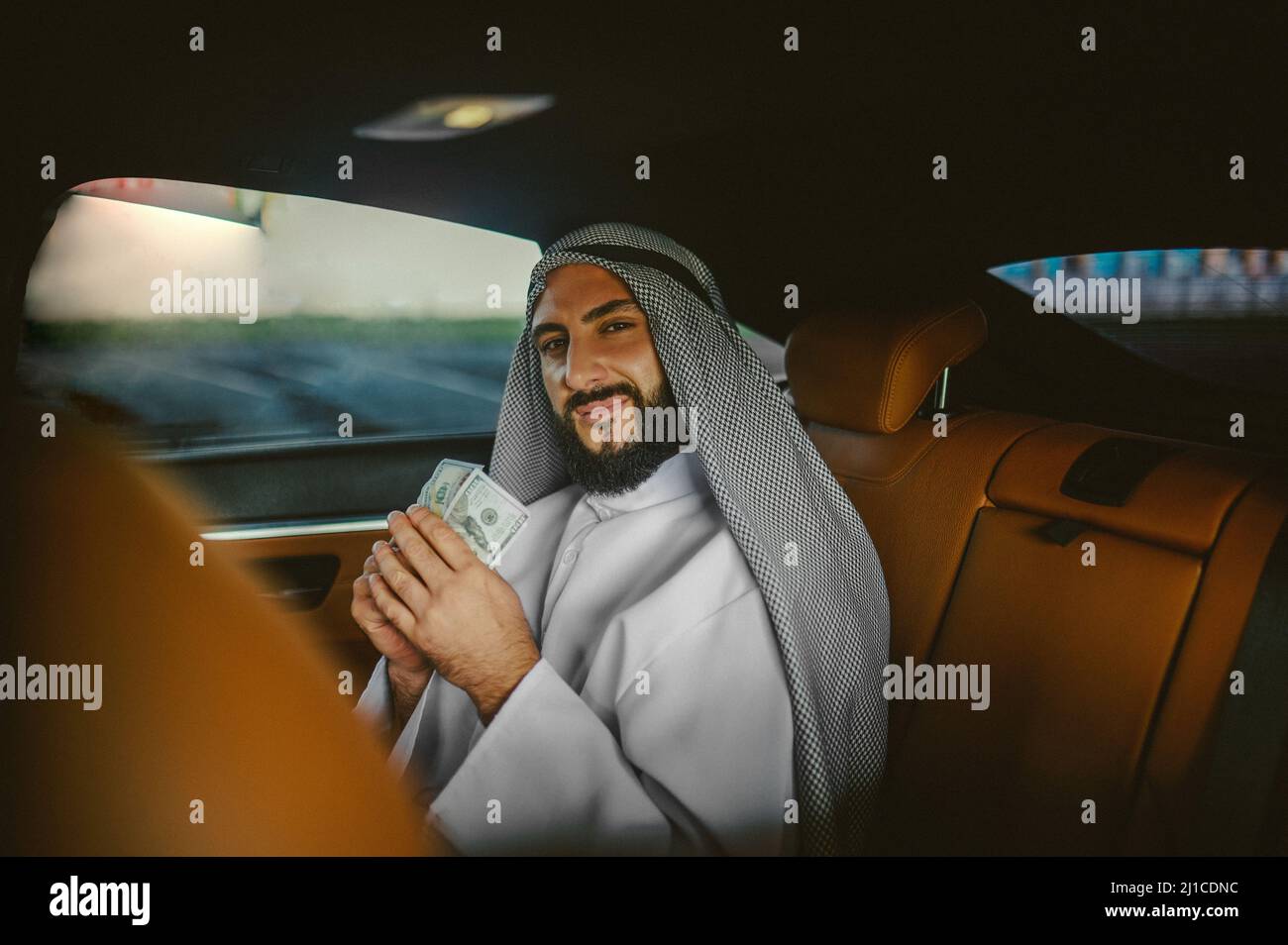 Saudi man in a traditional clothing in a car holding money Stock Photo ...