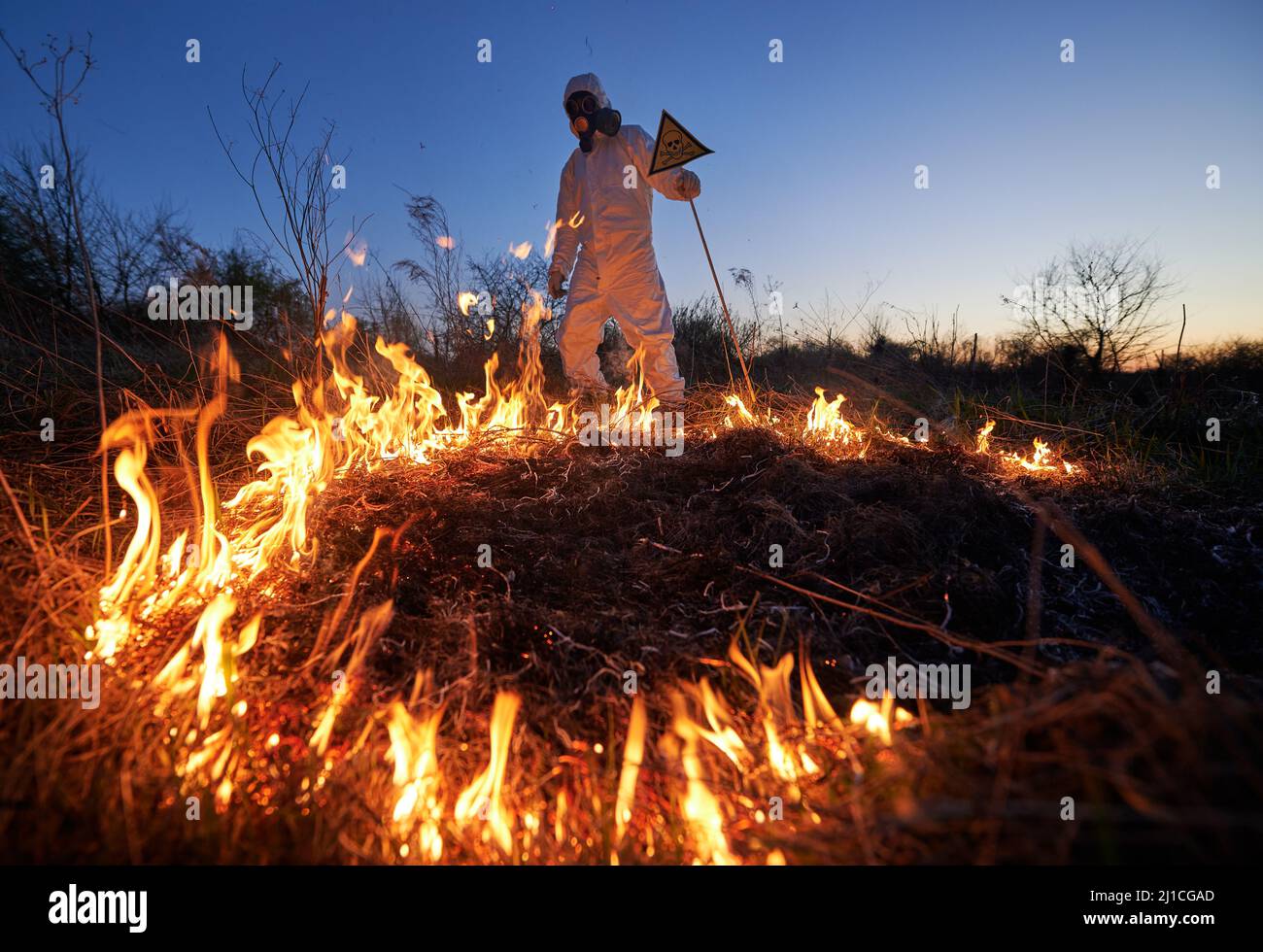 Fireman ecologist extinguishing fire in field at night. Man in ...