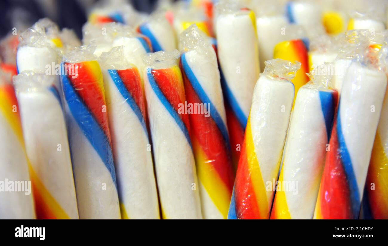 Background image shows a bunch of candy sticks that are striped blue ...