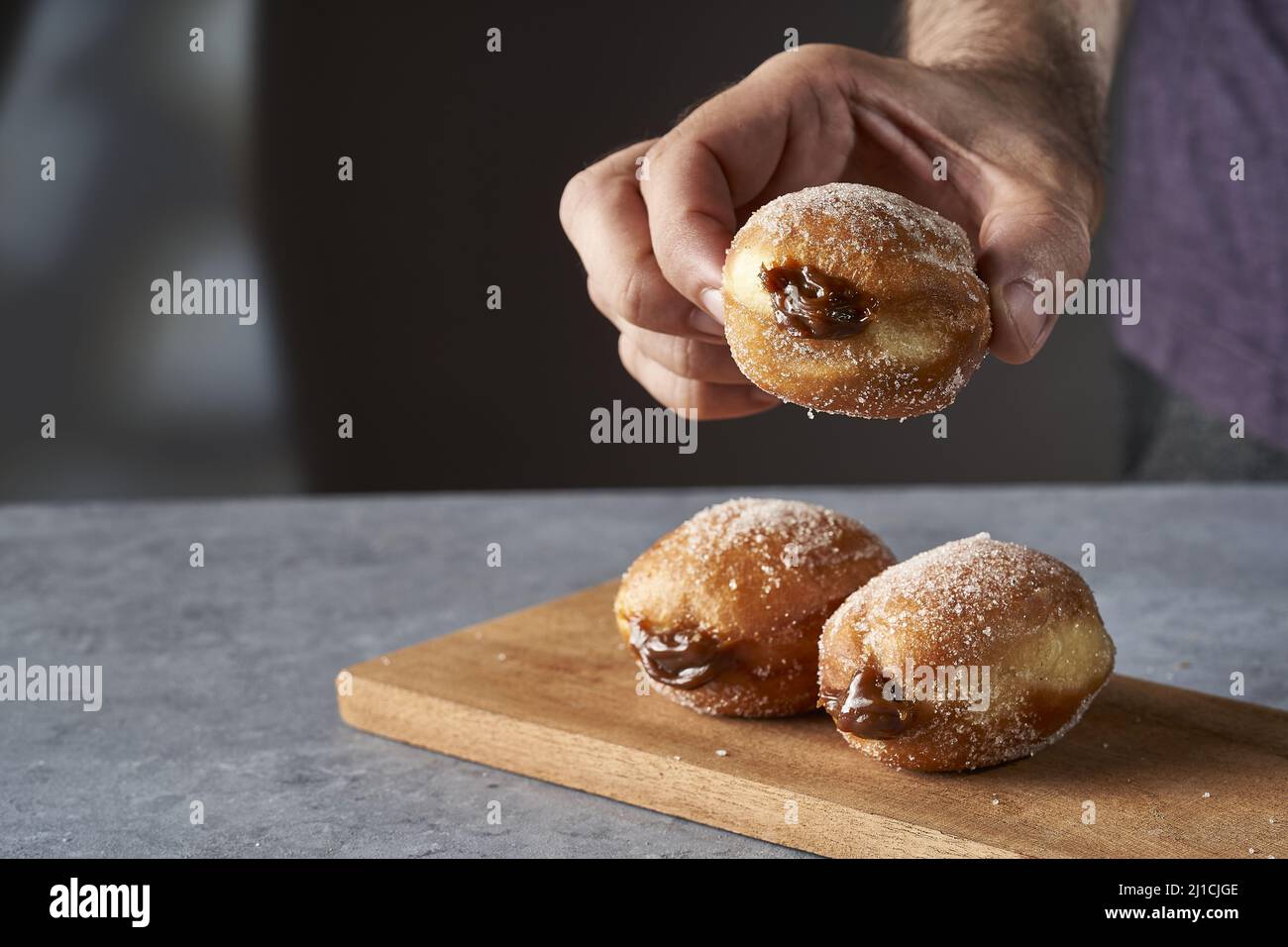 A closeup of a man's hand serving a sweet Berliner (berlin ball ...