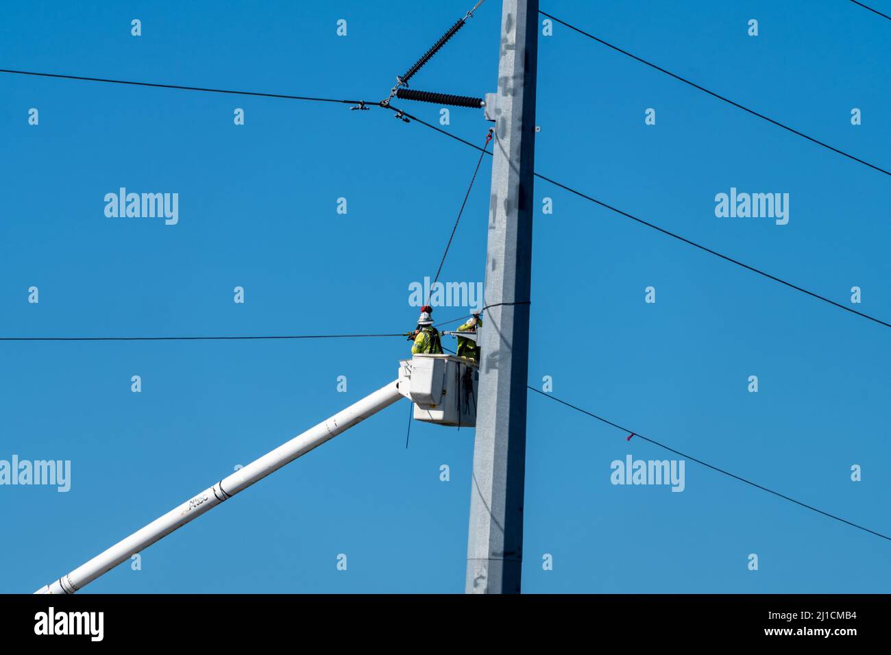 Electrical construction workers or linemen working in an elevated ...