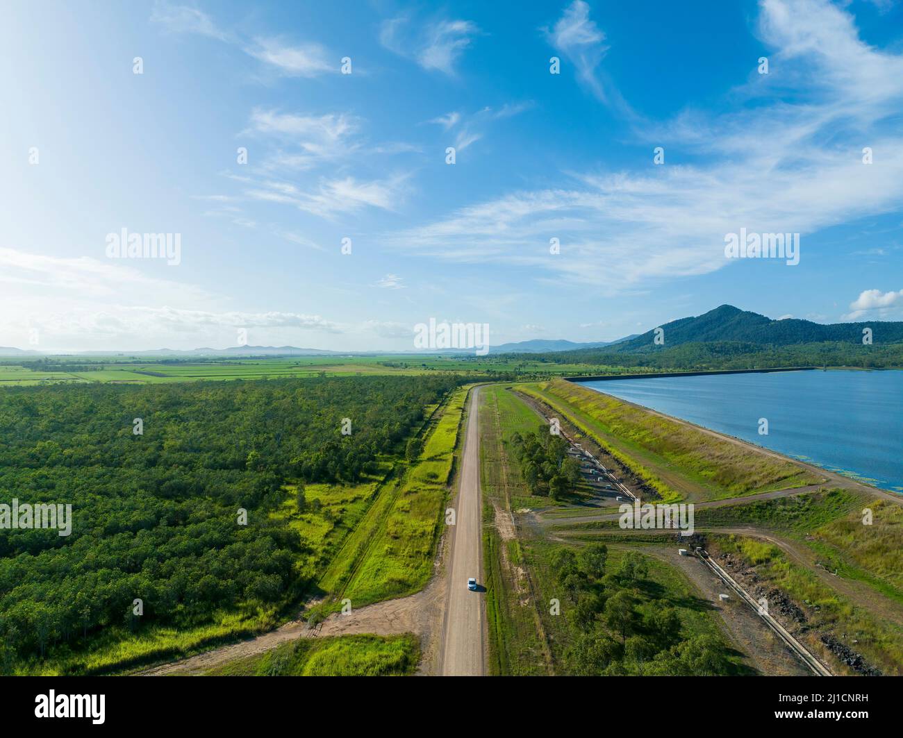 An aerial view of a dam wall with a car on the road beside it. Peaceful ...