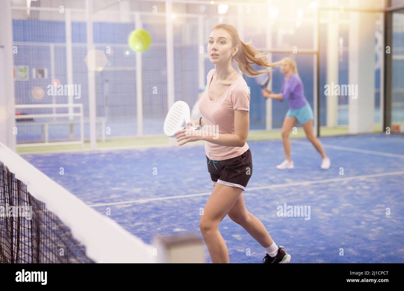 Woman serving ball while playing padel in court Stock Photo - Alamy