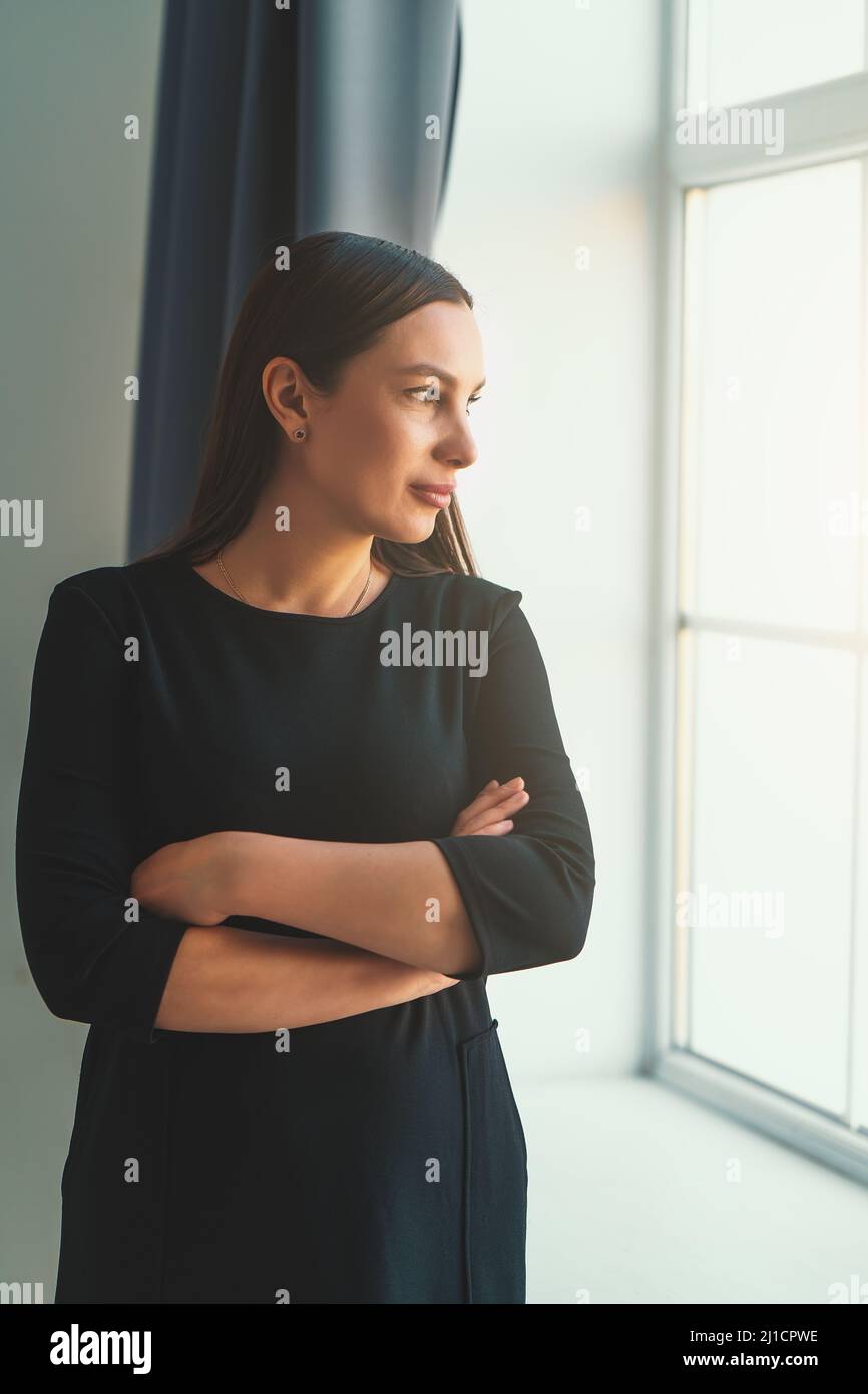 Young beautiful brunette girl or woman in black dress looks ...