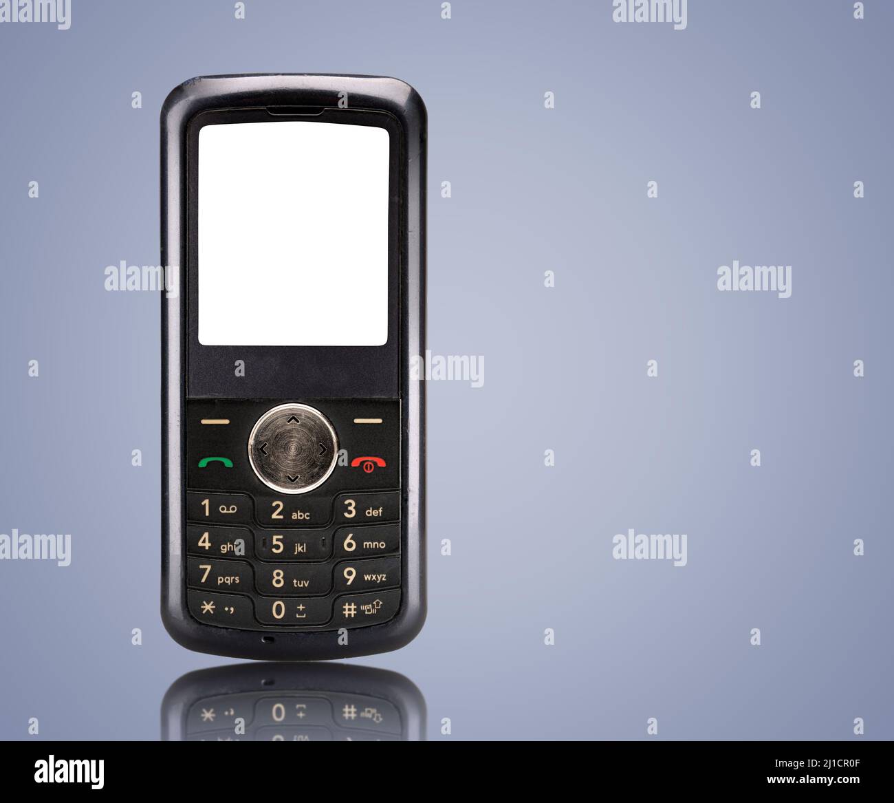 Old push-button mobile phone with a reflection on a blue background ...