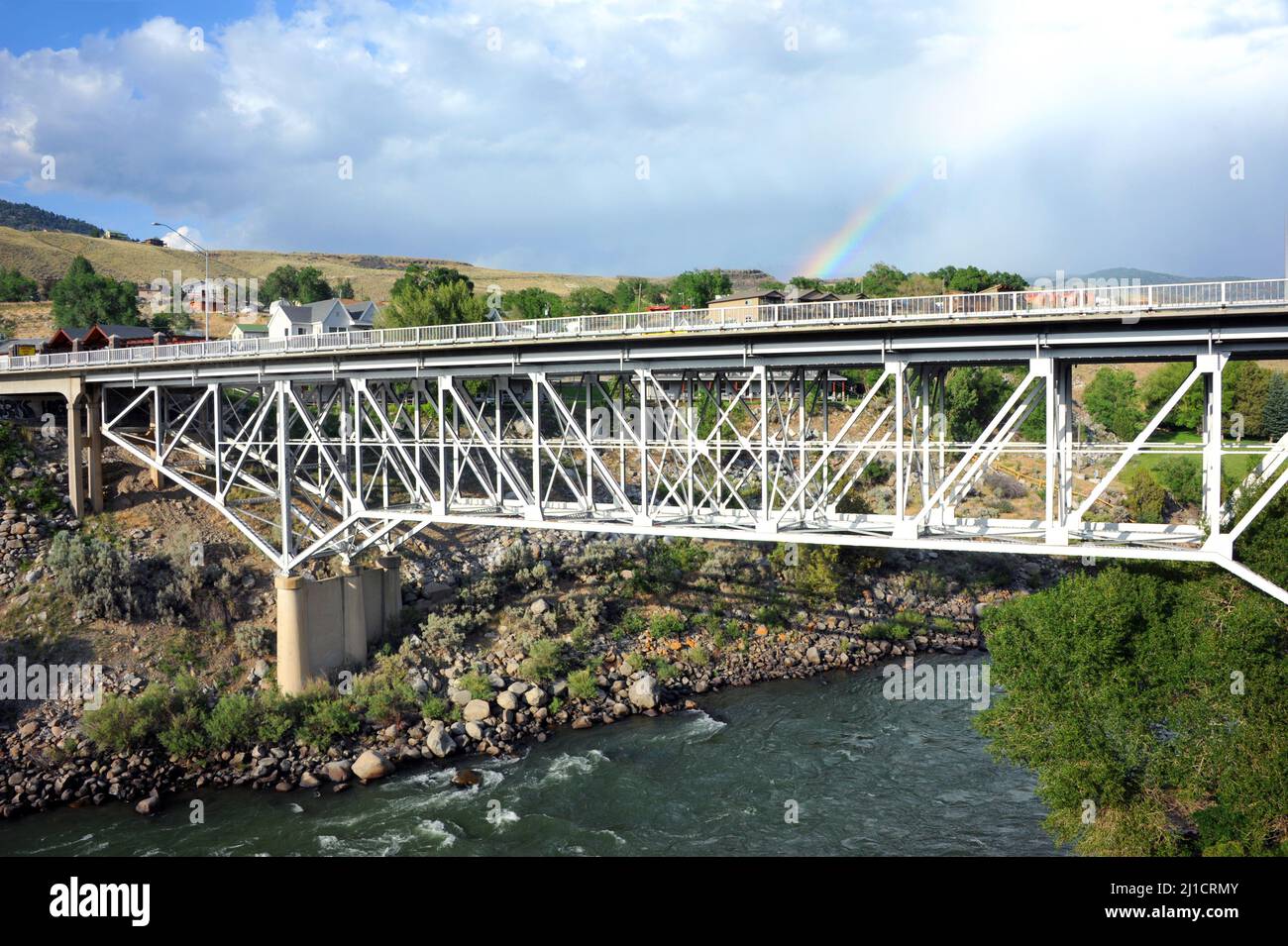 Metal bridge spans the Yellowstone River in Gardner, Montana. Rainbow ...