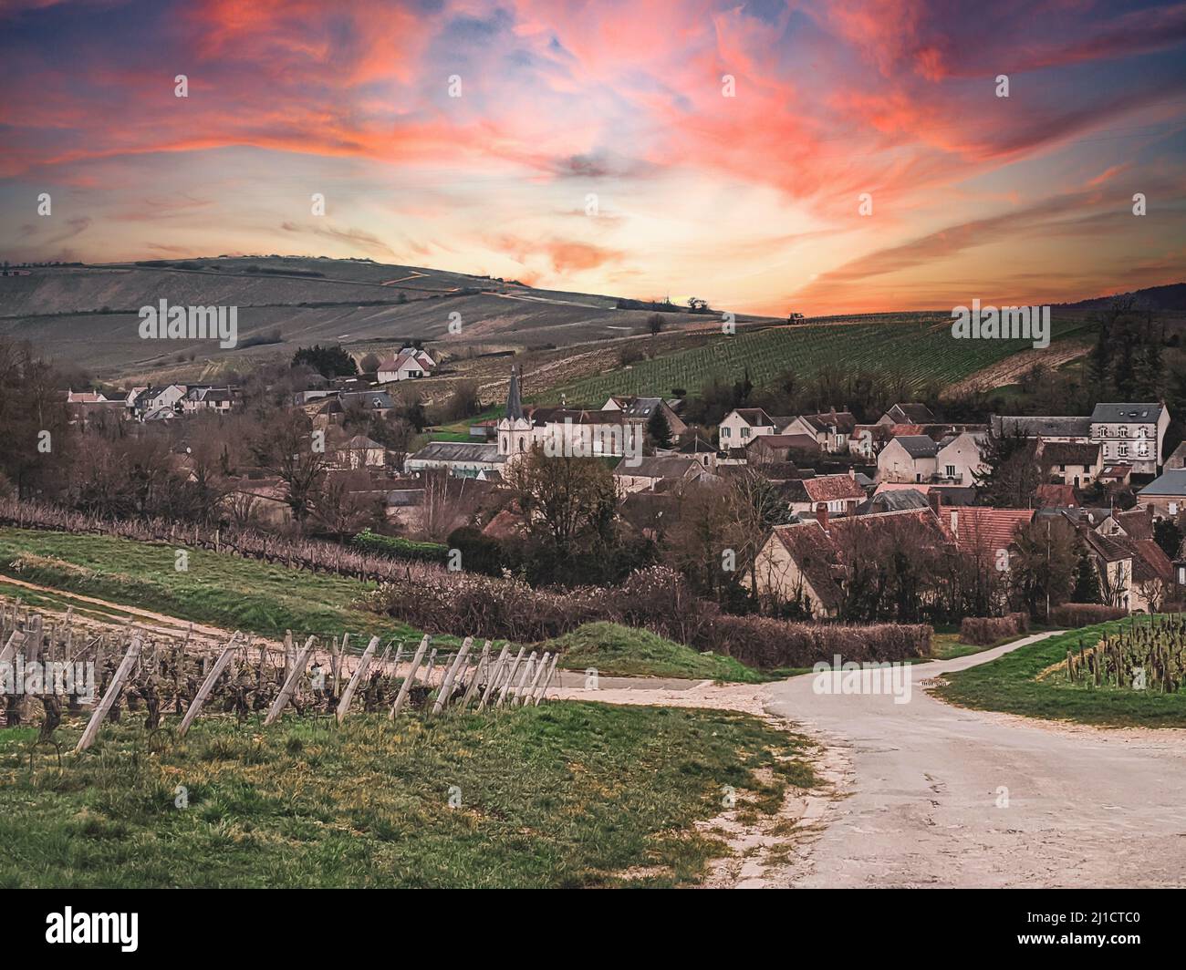 A gorgeous sunset scene in a village with pinkish clouds in the sky ...