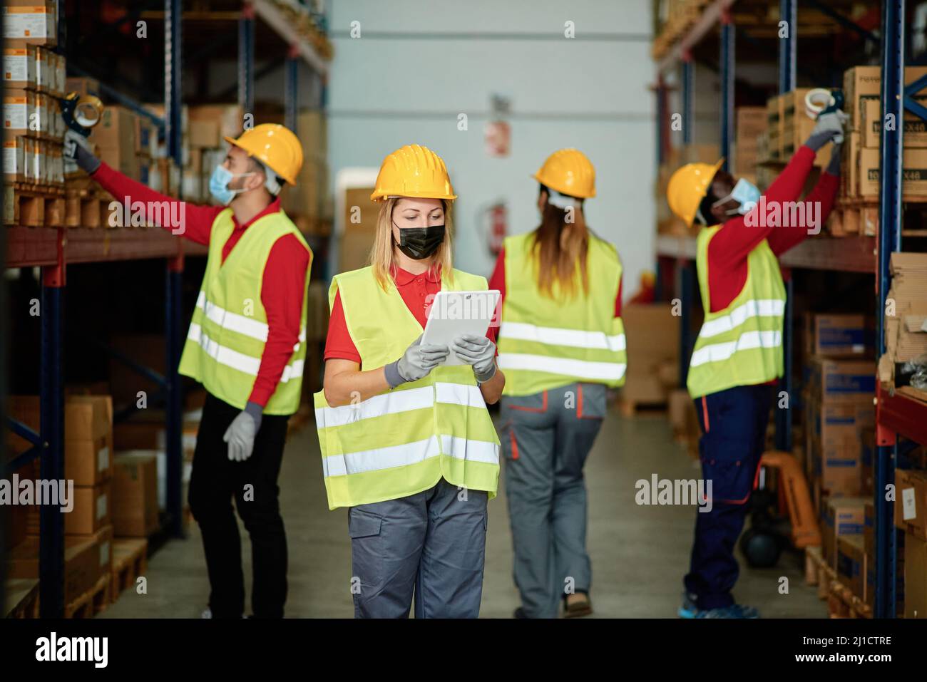 Portrait of happy female worker looking at camera inside warehouse ...