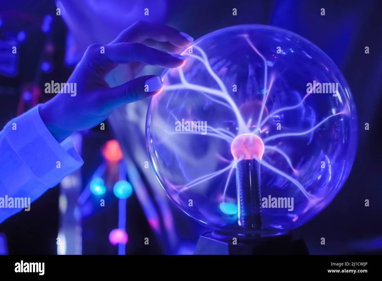 Woman hand touching plasma ball with many energy rays inside - close up ...