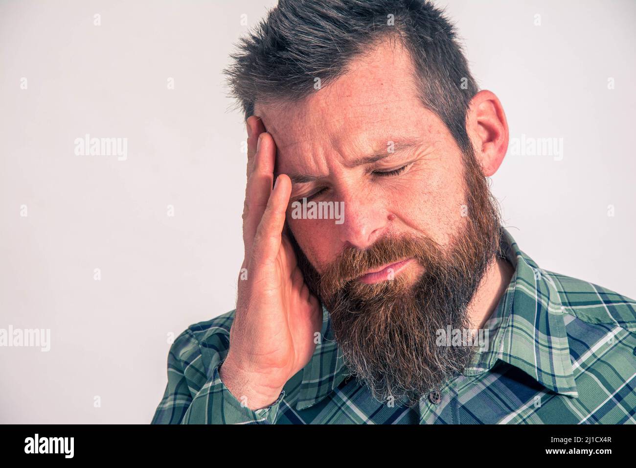 Upset man standing with his hand holding his forehead Stock Photo - Alamy