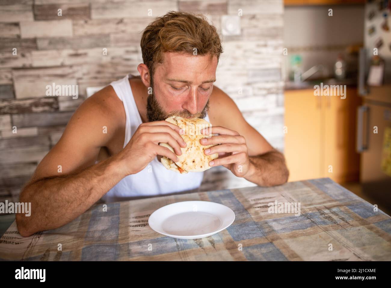 The blond young man eats a big tasty burger Stock Photo - Alamy