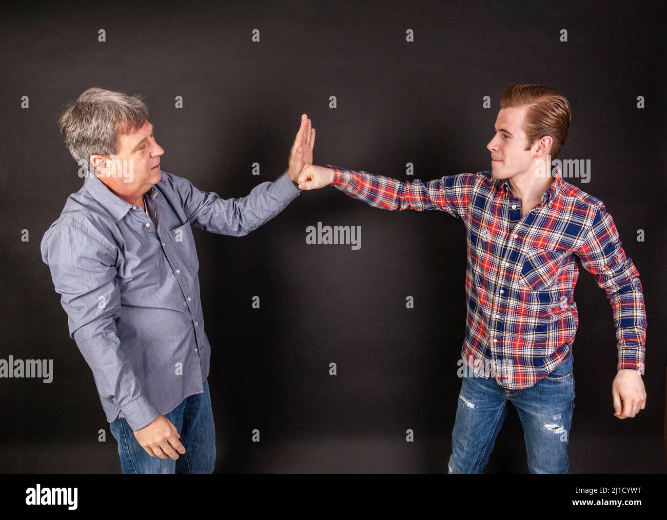 father and son lean on back to back isolated on black Stock Photo - Alamy