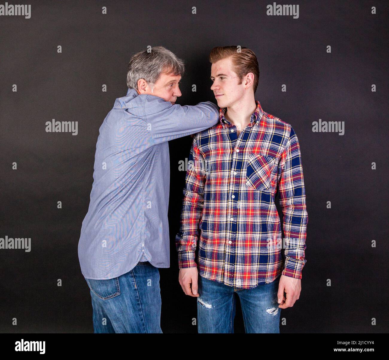 father and son lean on back to back isolated on black Stock Photo - Alamy