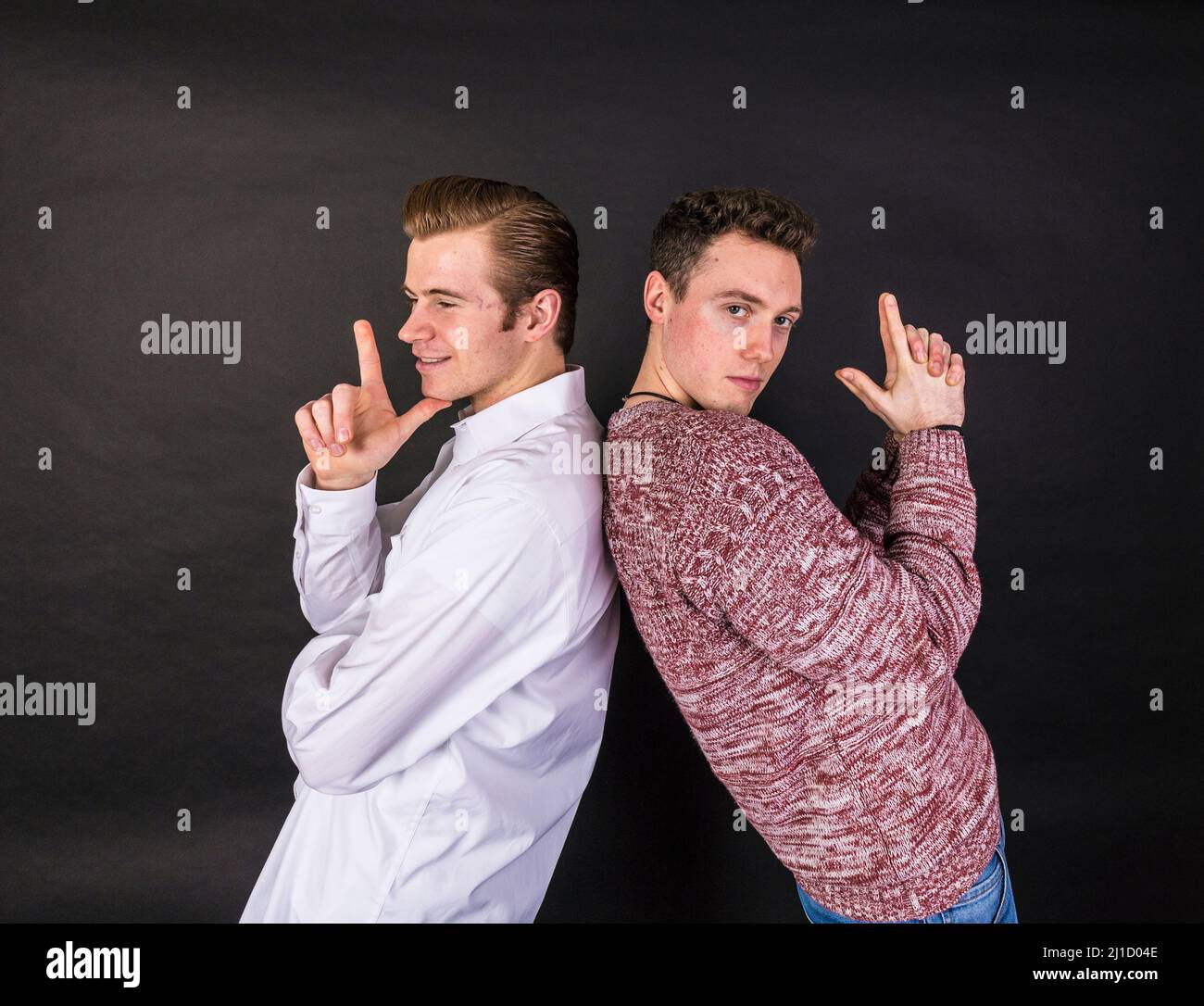 two teenage boys standing back to back and look cool Stock Photo - Alamy