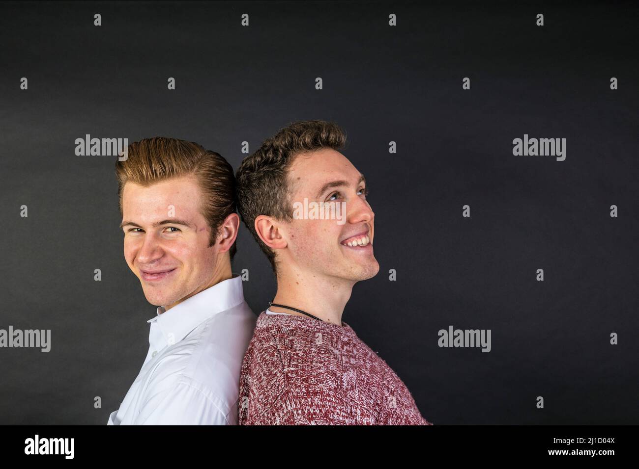 two teenage boys standing back to back and look cool Stock Photo - Alamy
