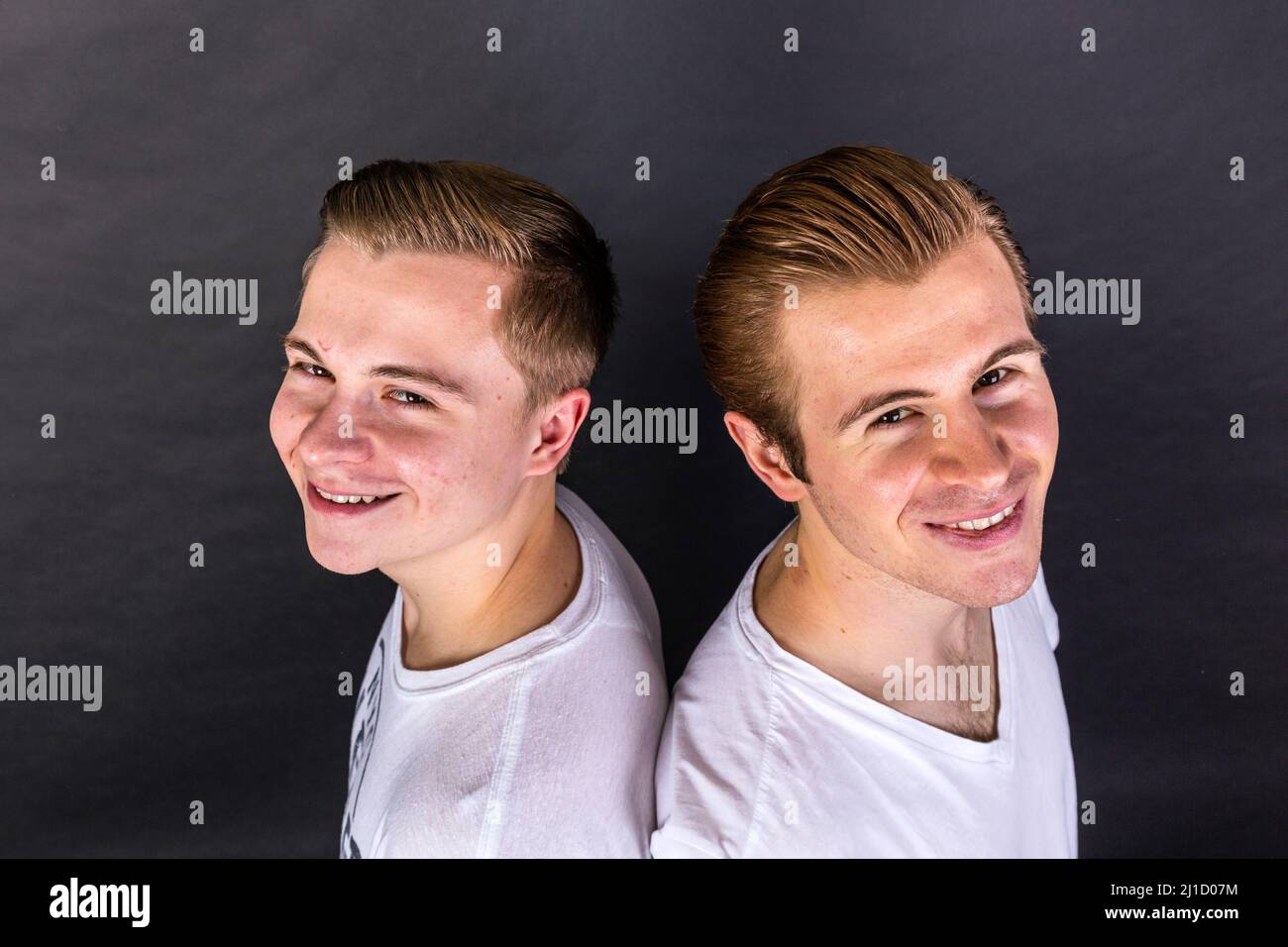 two teenage brothers standing back to back and have fun Stock Photo - Alamy