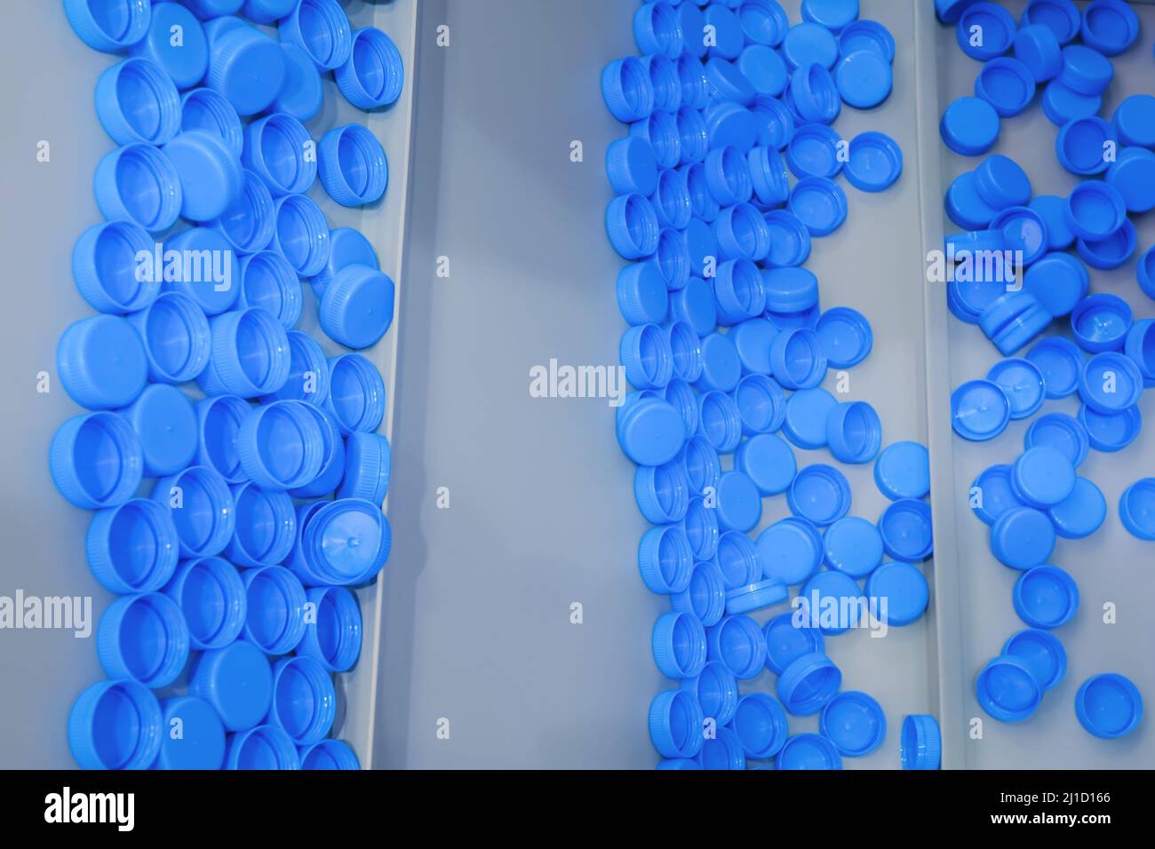 Many blue plastic bottle caps moving on conveyor belt - production line ...