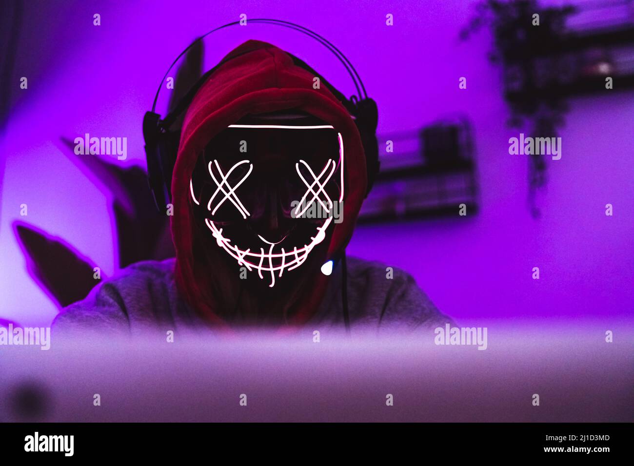 Masked hacker in action. Safety in the internet concept. Magenta color ...