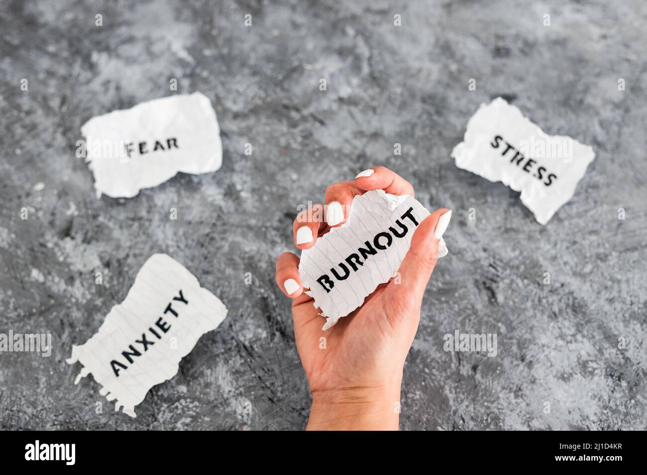 hand holding Burnout text on scrunched up piece of paper surrounded by ...