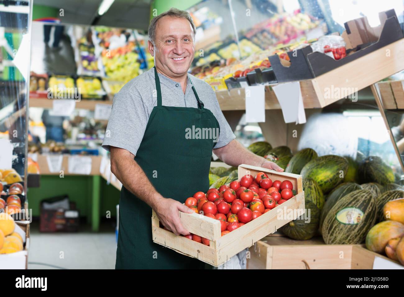 Smiling man employee showing box with natural tomatos Stock Photo - Alamy