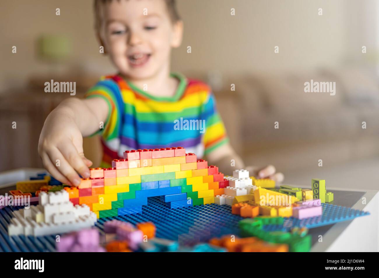 Confident male baby constructing tower with multicolored plastic pieces ...