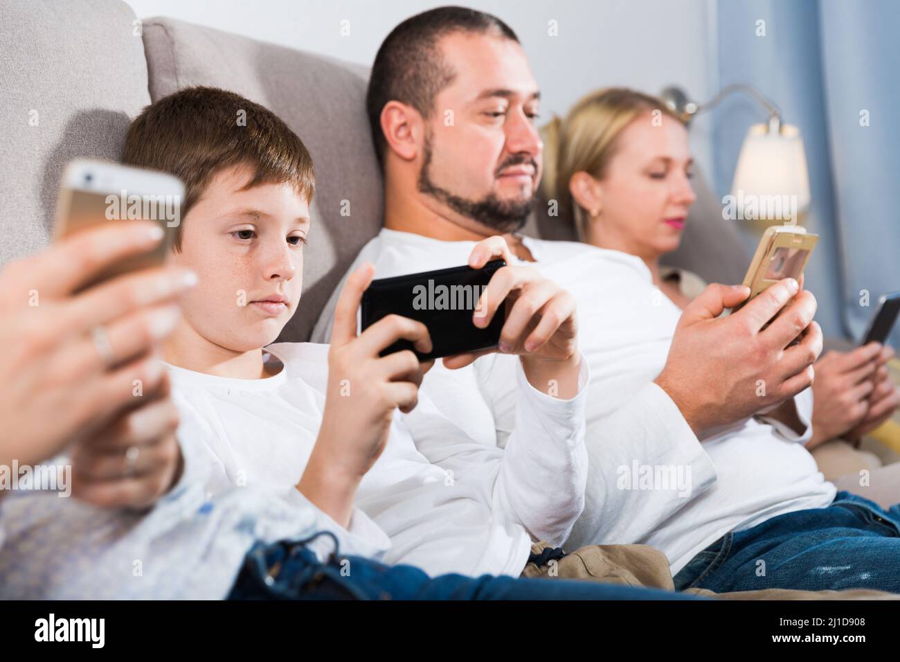 Parents and son using phones at home Stock Photo - Alamy