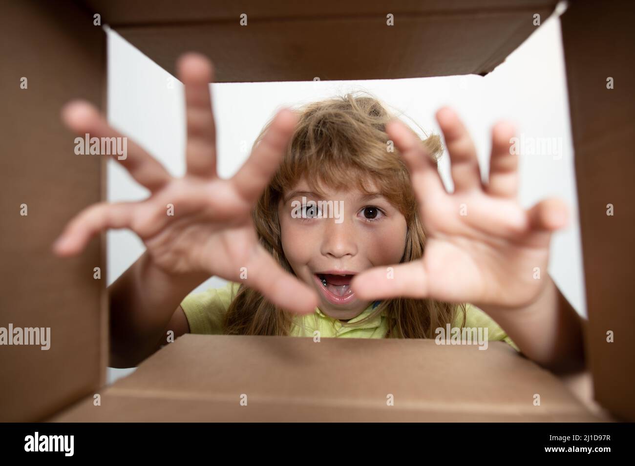 Child opens carton box and pulling out gift from it, take by hand gift ...