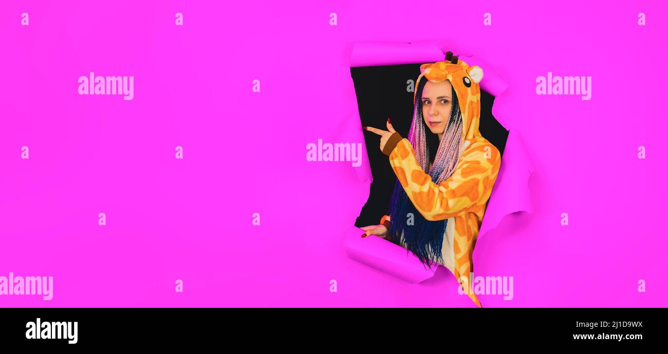 Young woman in pajamas of giraffe sticking out of hole of purple ...