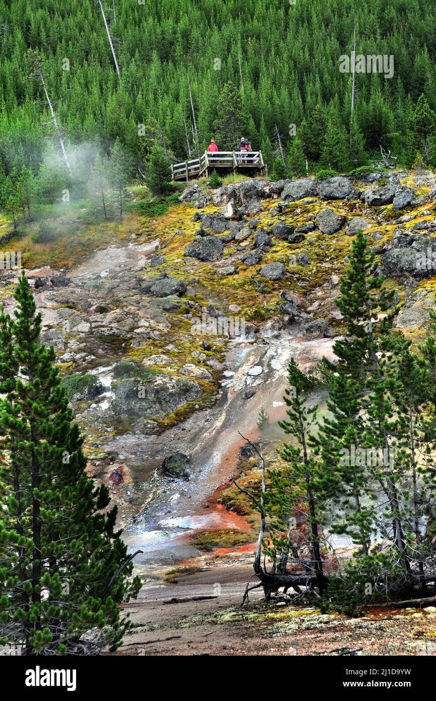 Perched on ridge overlooking thermal hot springs, visitors stand on ...