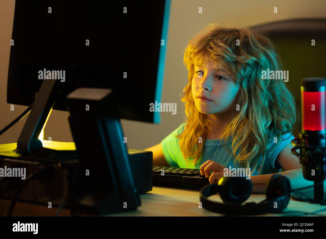 A little boy child uses a desktop at night, a child with computer ...
