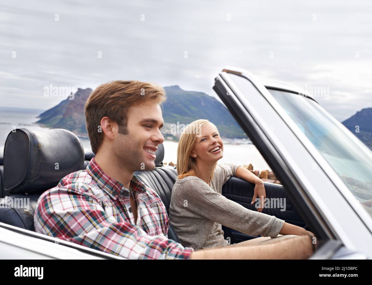 Sunday drive.... Shot of a young couple enjoying a drive in a ...