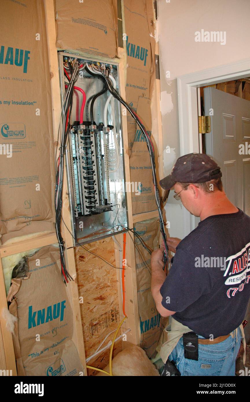 Electrician installing fans, lights and circuit panels and breakers on ...