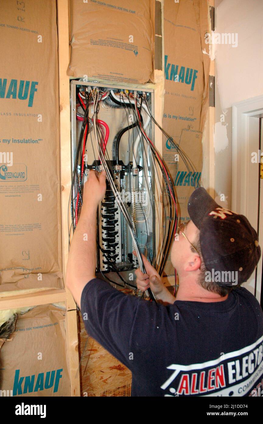 Electrician installing fans, lights and circuit panels and breakers on ...