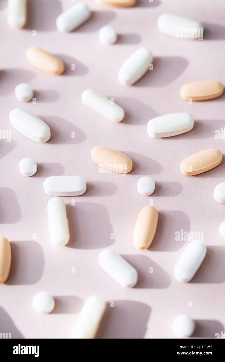 Different pills, vitamin capsules on pastel pink background. Dietary ...