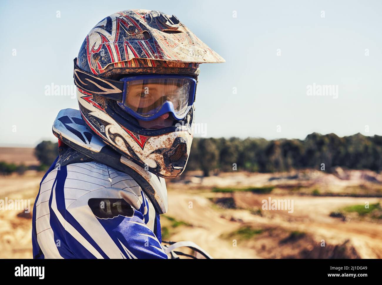 Time to rip up this track. Portrait of motocross rider looking back ...
