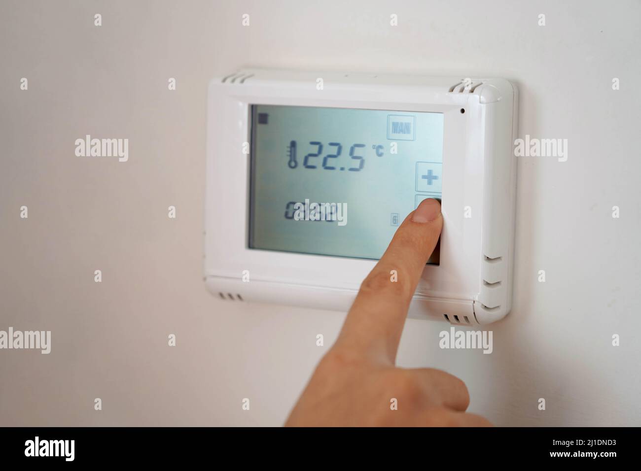 Saving energy concept: human hand turning down temperature on digital ...