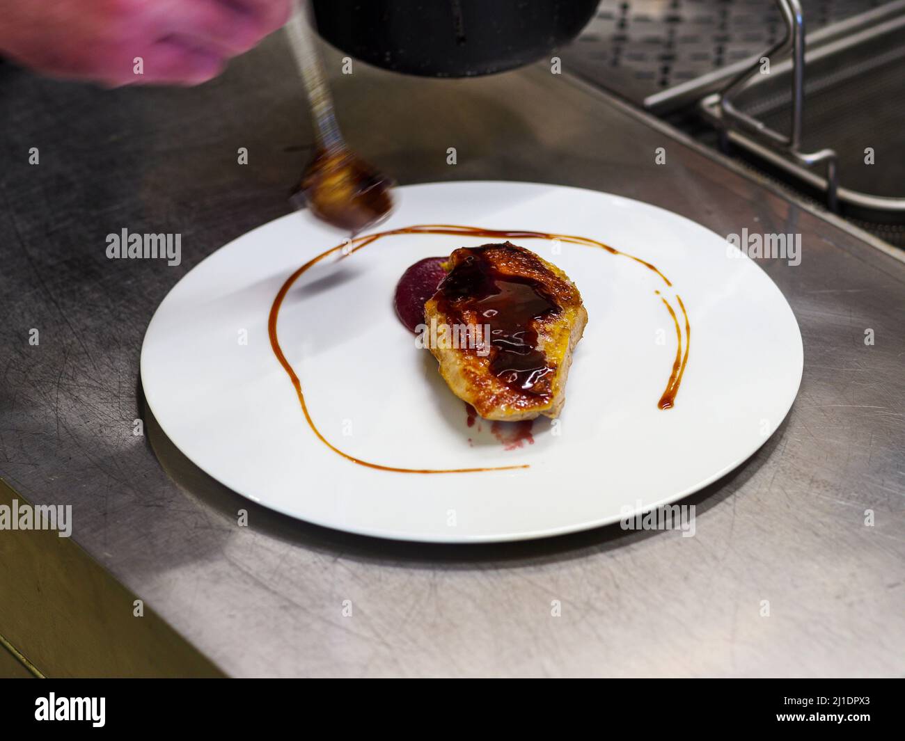 chef plating a main course with chiken and vegetables on a restaurant ...