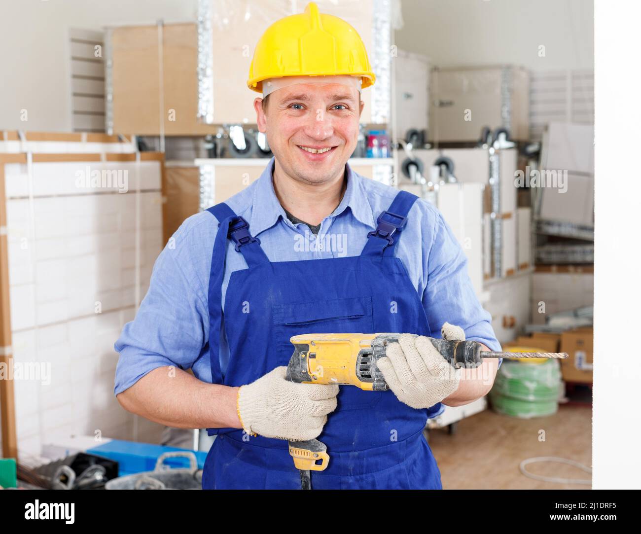 Confident construction worker is holding an electric drill hi-res stock ...