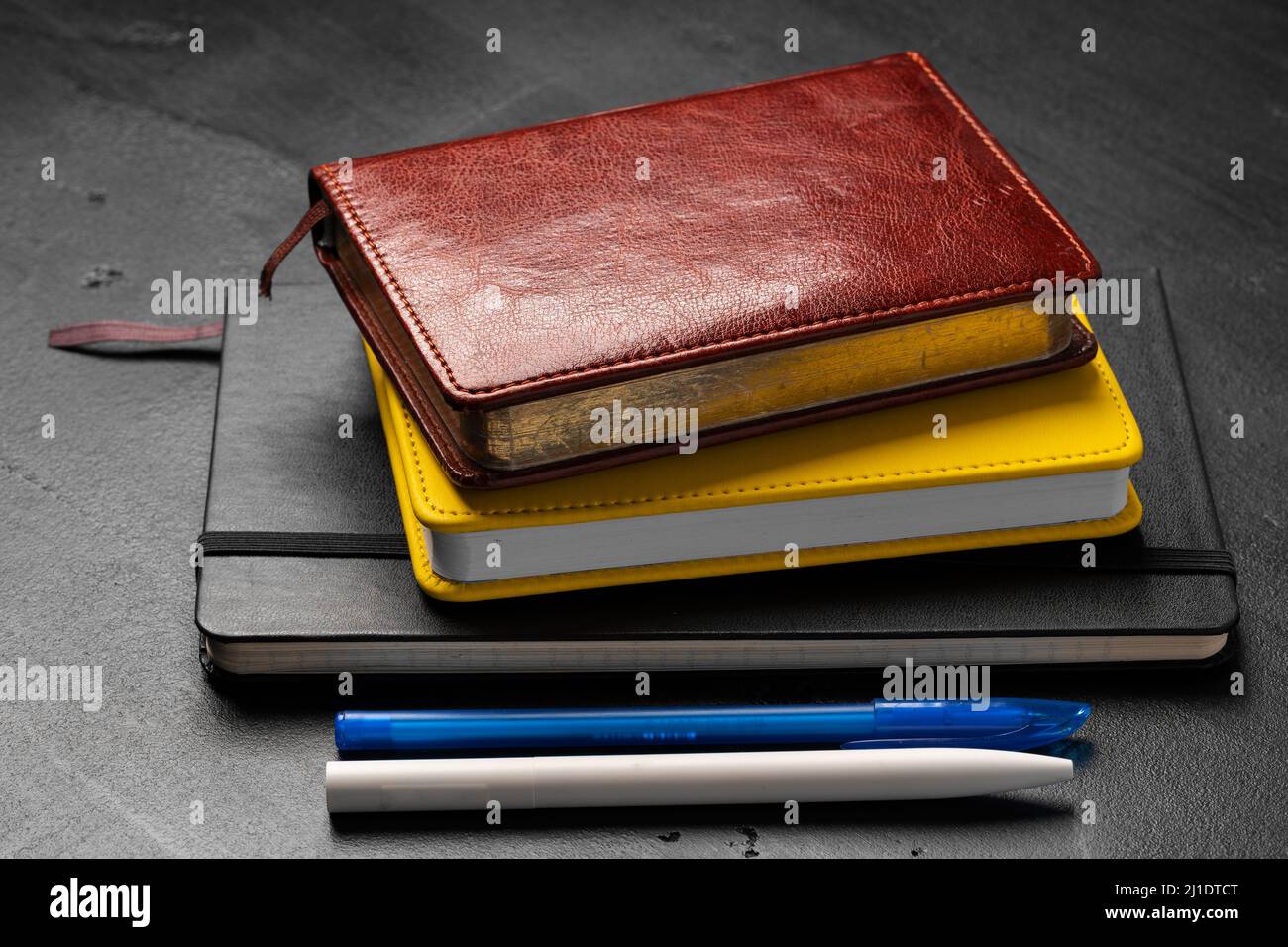 Three notepads on a black table close up Stock Photo - Alamy