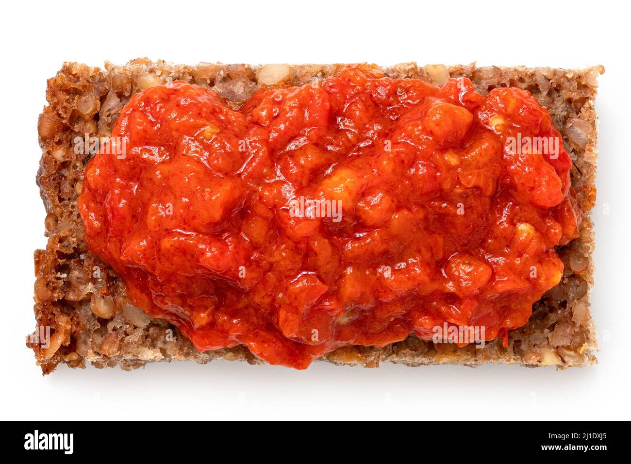 Ajvar spread on a slice of health bread isolated on white. Top view ...